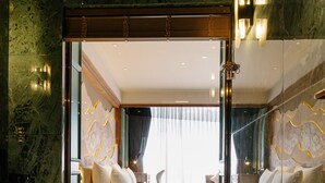 Quarto de hotel moderno com uma cama grande, um jacuzzi envidraçado e vista para a paisagem urbana.