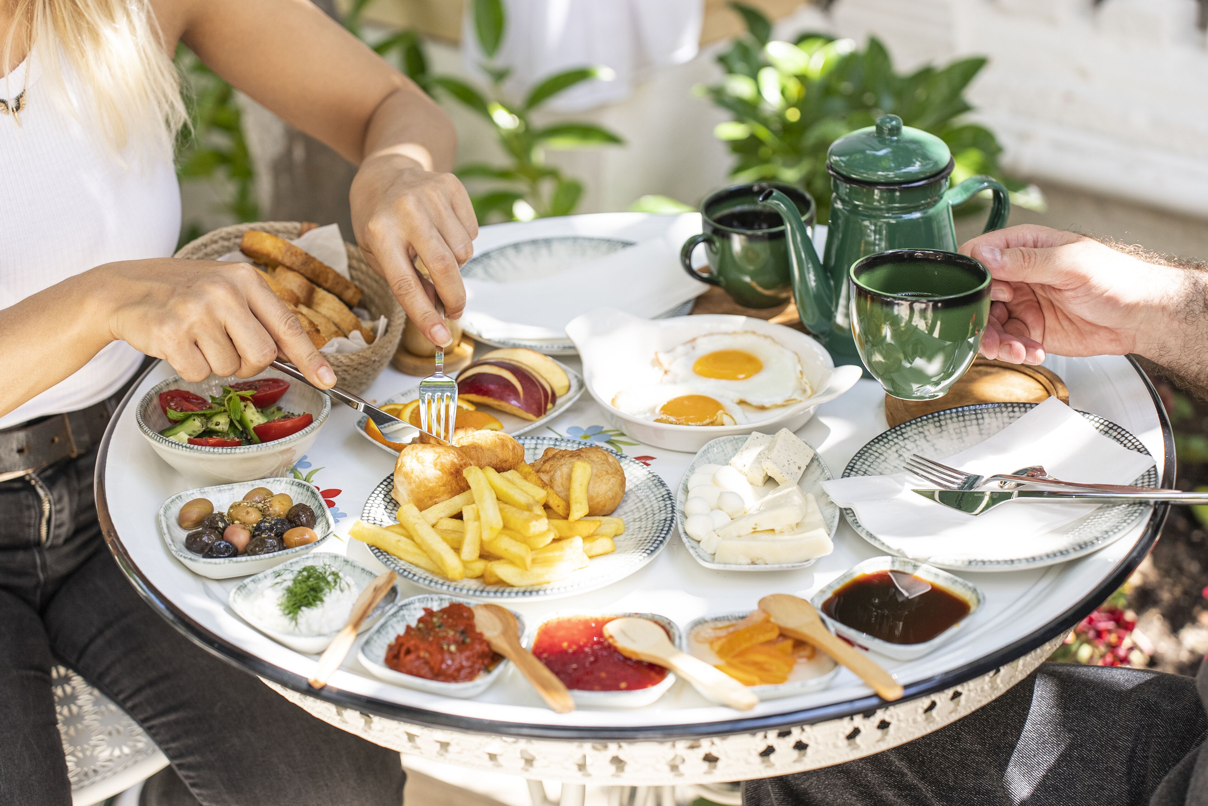 Uma mesa de jantar redonda com uma variedade de pratos, incluindo peixe, batatas fritas, ovos e saladas.