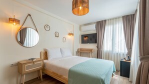 Quarto bem organizado com cama, mesa de cabeceira, espelho, luminárias na parede e um aparelho de ar condicionado.