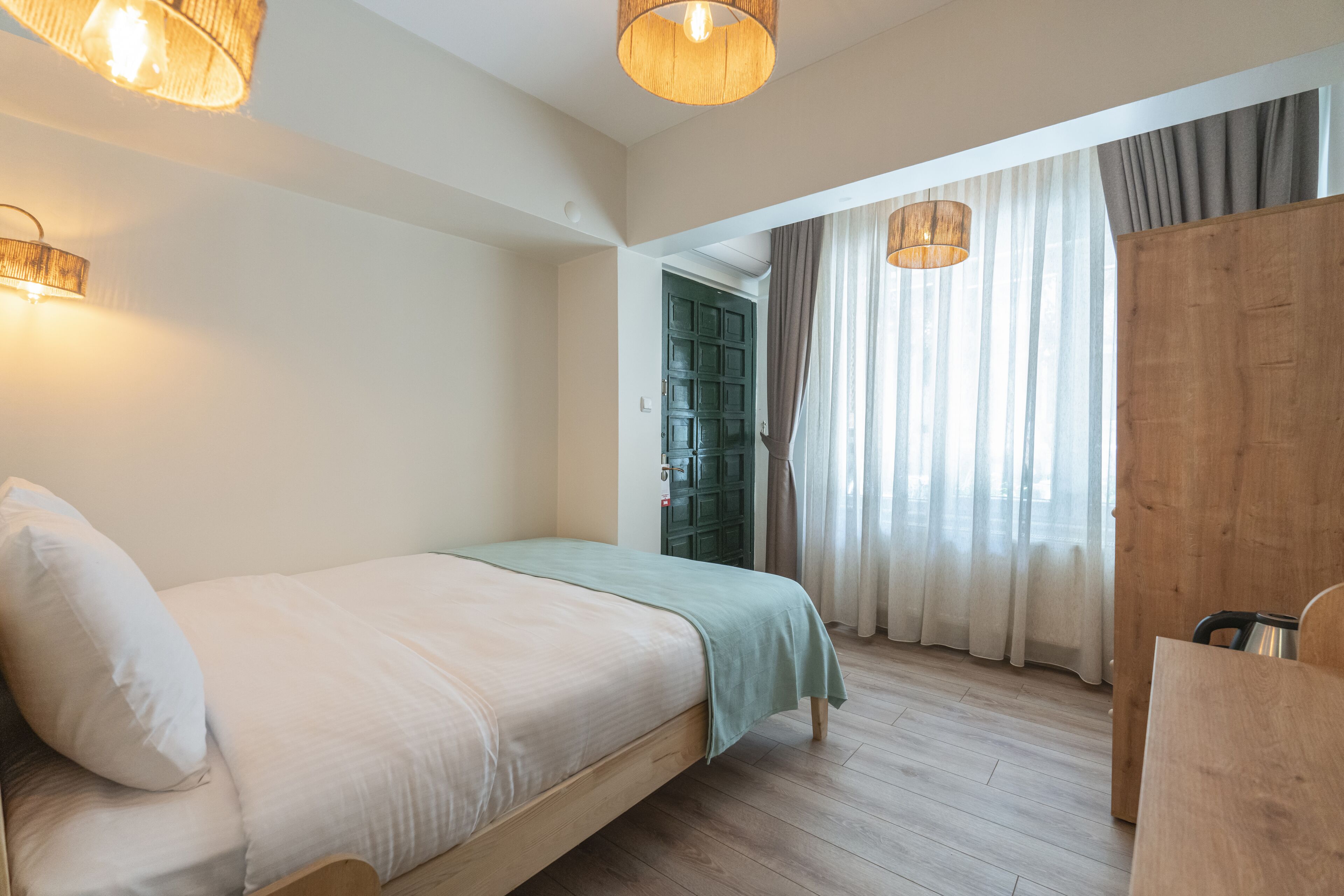 Quarto com cama, guarda-roupa de madeira e porta verde.