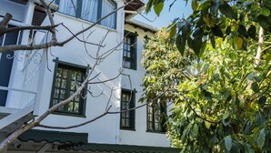 Um edifício branco com persianas verdes e uma varanda.