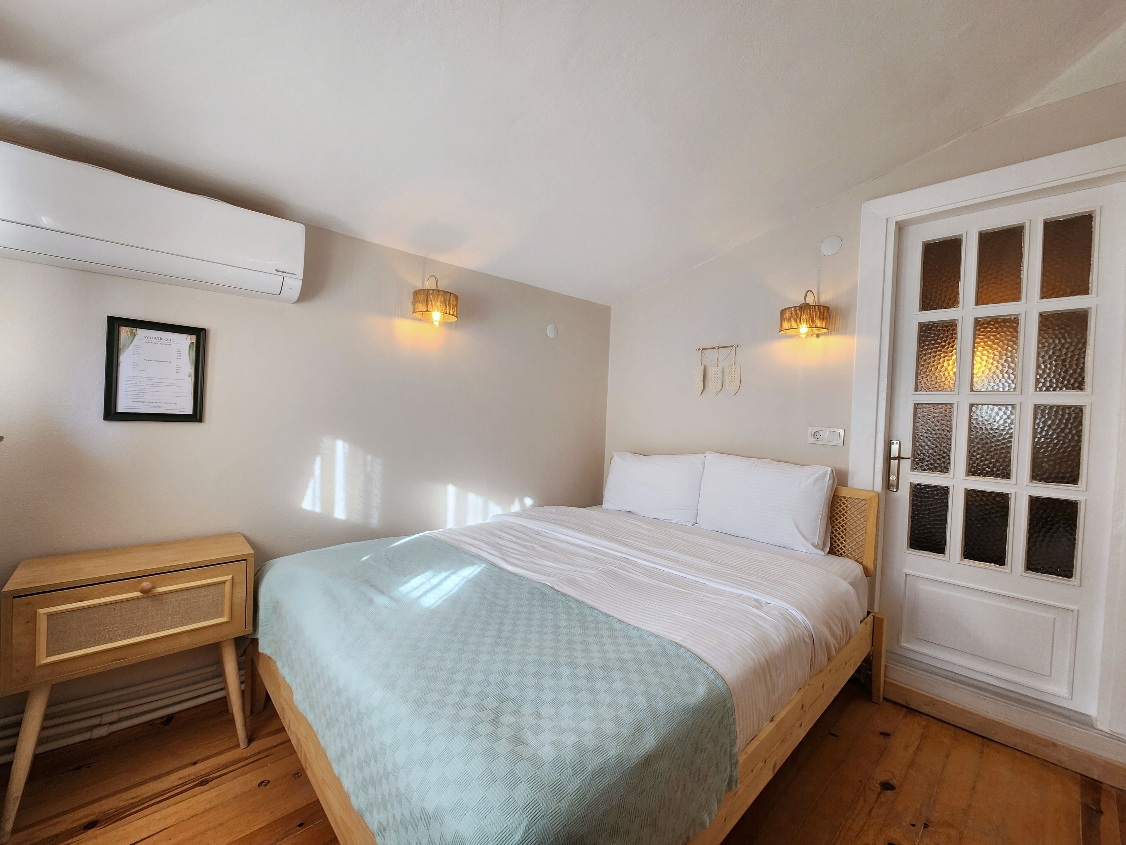 Quarto com cama, mesa de cabeceira e porta com painéis de vidro jateado.