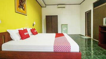 Quarto de hotel com cama, guarda-roupa, televisão e um quadro na parede.