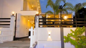 Um edifício moderno com fachada branca, entrada com portão e iluminação externa.