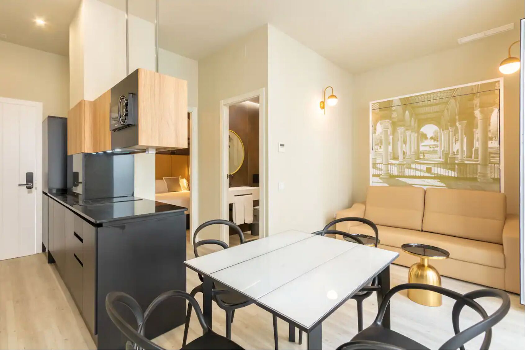 Um apartamento moderno com cozinha, área de refeições e sala de estar com sofá e um quadro.