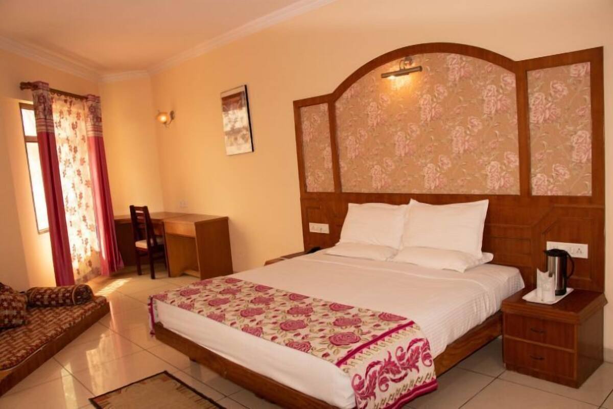 Quarto de hotel com uma cama grande, uma escrivaninha, uma cadeira e um sofá.