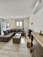 Uma sala de estar moderna com um sofá seccional, uma mesa de centro de madeira e um rack para televisão.