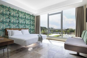 Quarto de hotel moderno com uma cama grande, uma escrivaninha e vista para o exterior.