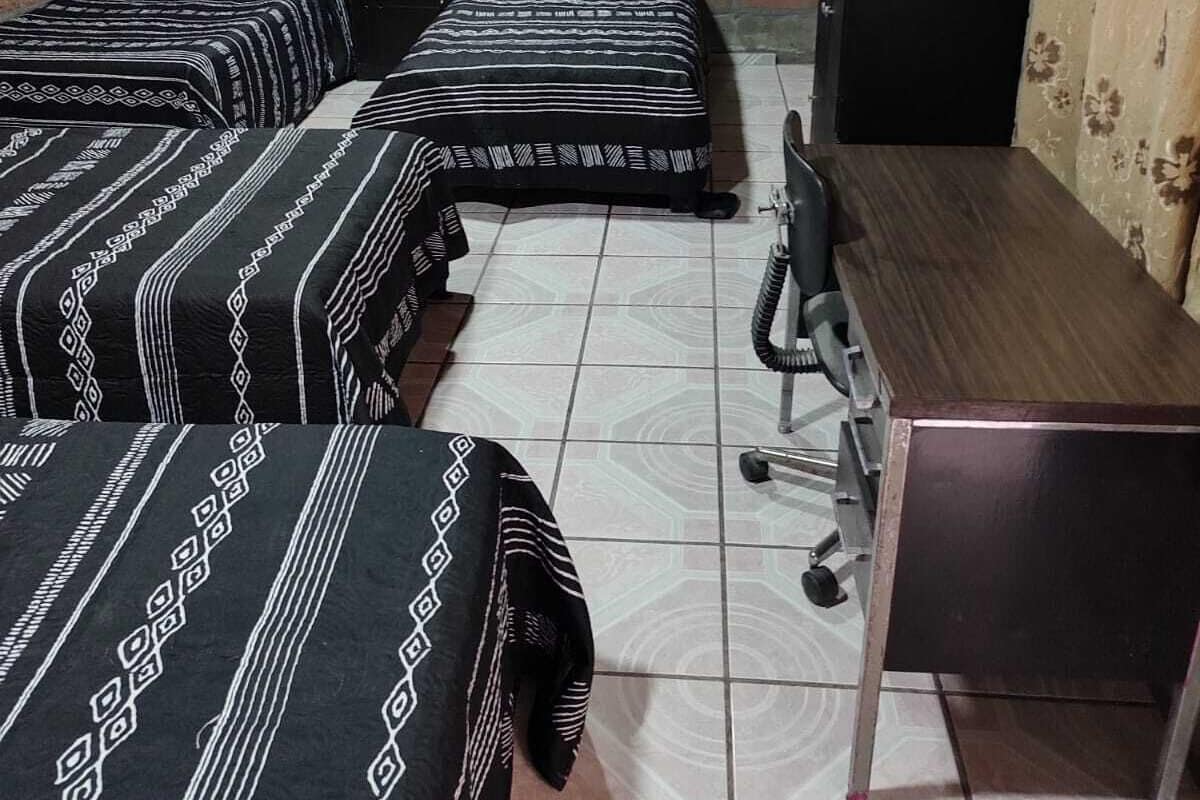 Quarto com duas camas, uma escrivaninha e um armário.