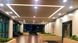 Corredor interior moderno com iluminação embutida, portas de vidro e vasos com plantas.