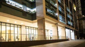 Um edifício moderno com grandes janelas e uma placa com a inscrição "ONE UPTOWN".