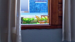 Quarto com vista para uma construção de telhado de palha e uma piscina.