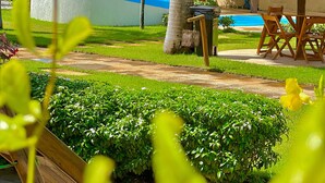 Resort com piscina, estruturas com telhados de palha e área de refeições.