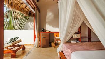 Quarto com cama, escrivaninha, cadeira, pequeno frigorífico e janela com vista para palmeiras.