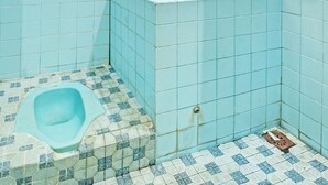 Um banheiro pequeno com azulejos azuis, vaso sanitário e banheira.