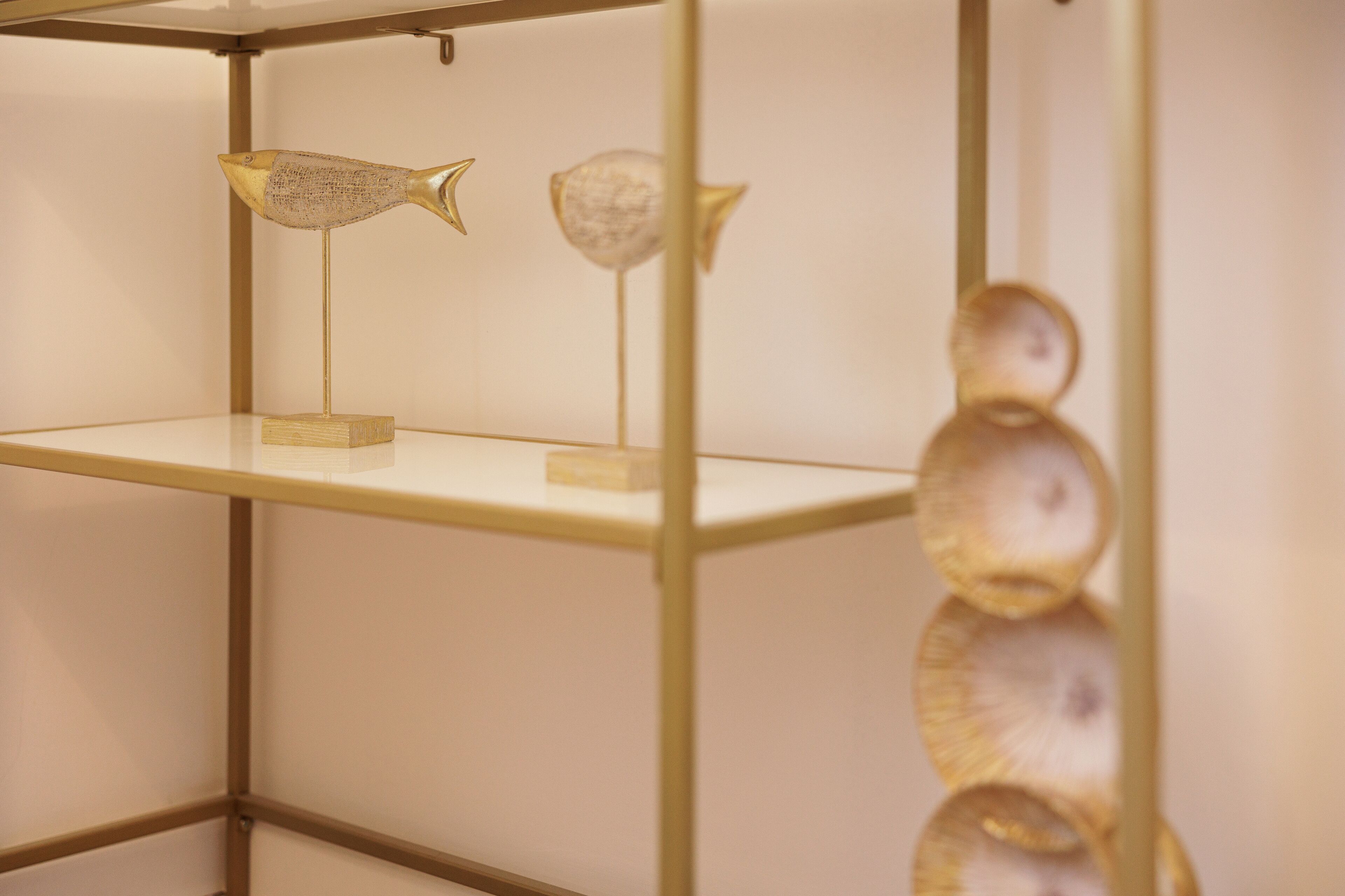 Exposição com duas esculturas em formato de peixe numa prateleira.