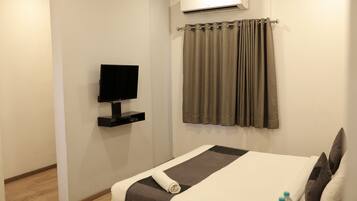 Quarto de hotel com cama, televisão de tela plana, ar condicionado fixado na parede e cortina.