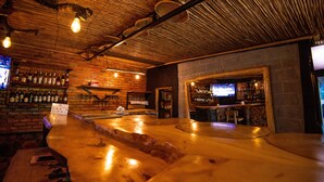 Um bar com balcão de madeira, paredes de tijolo e luminárias pendentes.