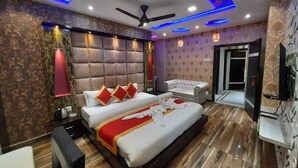 Quarto de hotel moderno com uma cama grande, um ventilador de teto e um espaço de estar.