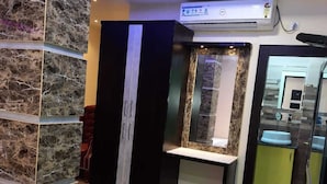 Quarto de hotel moderno com parede decorada em mármore, uma cama grande, toucador com espelho e ar condicionado.