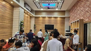 Uma sala de jantar com paredes de madeira, uma televisão de tela plana na parede e um teto com luminária decorativa.