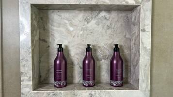 Três frascos de shampoo e condicionador Vinotage Merlot sobre uma prateleira de mármore.