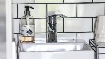 Uma casa de banho com uma pia branca, um espelho e um frasco de sabonete líquido.