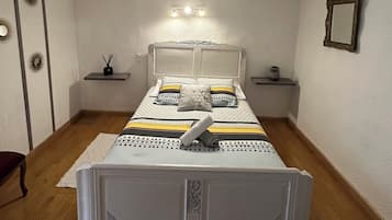 Quarto bem arrumado com cama, mesas de cabeceira e um espelho na parede.
