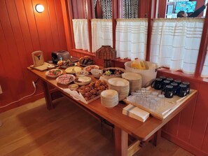 Uma mesa de buffet com diversos alimentos, pratos e copos.