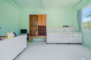 Um quarto com uma escrivaninha, um computador, um armário de madeira e um móvel de armazenamento branco.