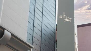 Um edifício de hotel moderno com uma placa vertical exibindo o nome 'BUPYEONG' e a palavra 'HOTEL' no topo.