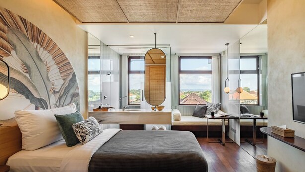 Quarto de hotel moderno com uma cama grande, uma escrivaninha, um espelho e vista para a paisagem.