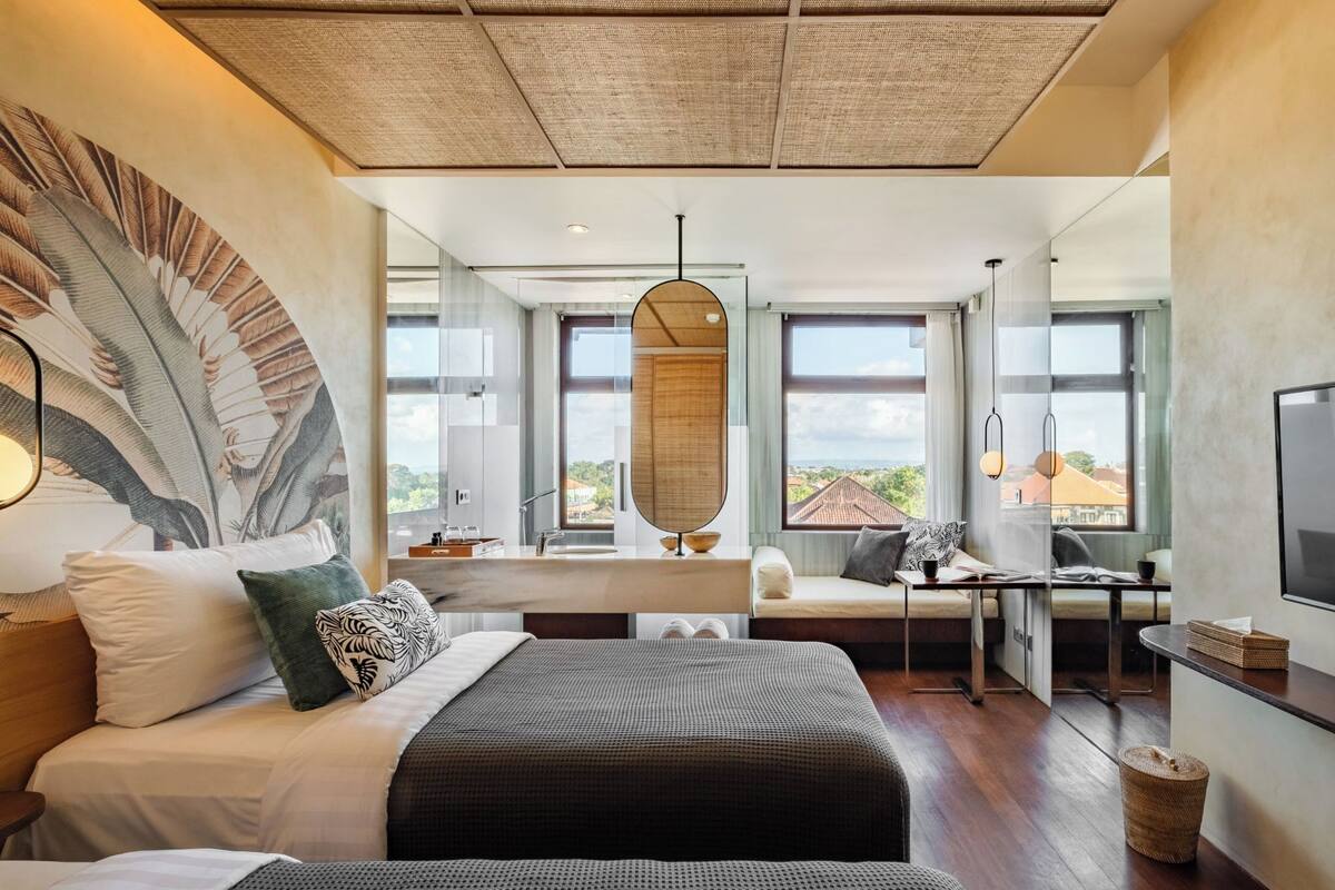 Quarto de hotel moderno com uma cama grande, uma escrivaninha, um espelho e vista para a paisagem.