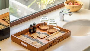 Bandeja de madeira com vários artigos de higiene pessoal em uma bancada de banheiro.