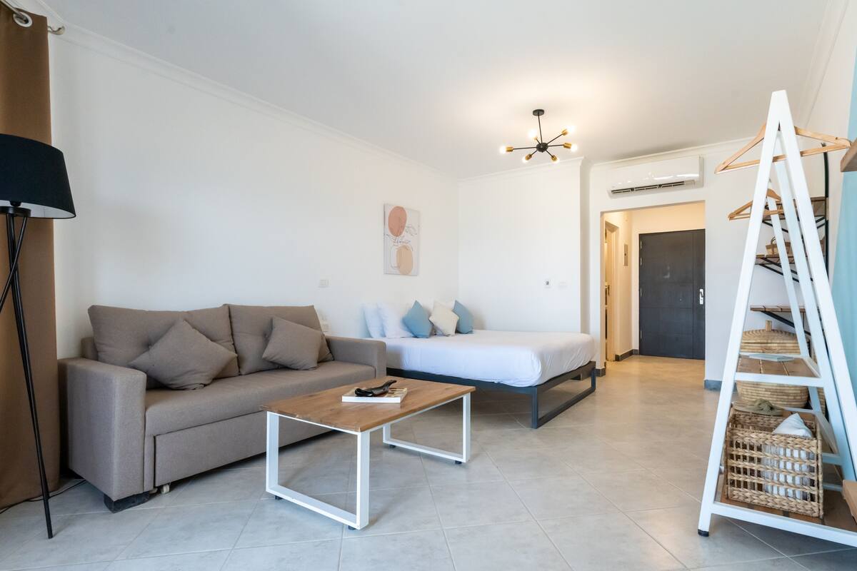 Uma sala de estar moderna com um sofá, uma mesa de centro, uma cama e um lustre.