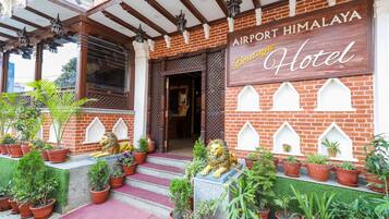 Exterior do Hotel Airport Himalaya Boutique, com fachada de tijolos, estátuas decorativas de leões e plantas em vasos.