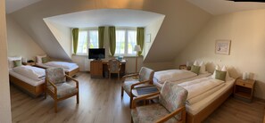 Quarto de hotel com duas camas, uma mesa, uma cadeira e uma televisão.