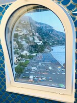Janela com vista para uma vila costeira, edifícios e barcos na praia.