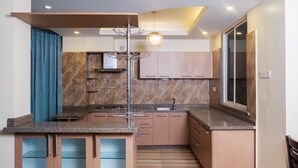 Cozinha moderna com ilha central, armários embutidos e luminária pendente.