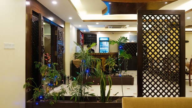 Uma área de recepção com balcão, plantas em vasos e um painel decorativo de madeira.