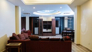 Uma sala moderna com um sofá seccional, uma televisão e uma área de jantar com mesa e cadeiras.