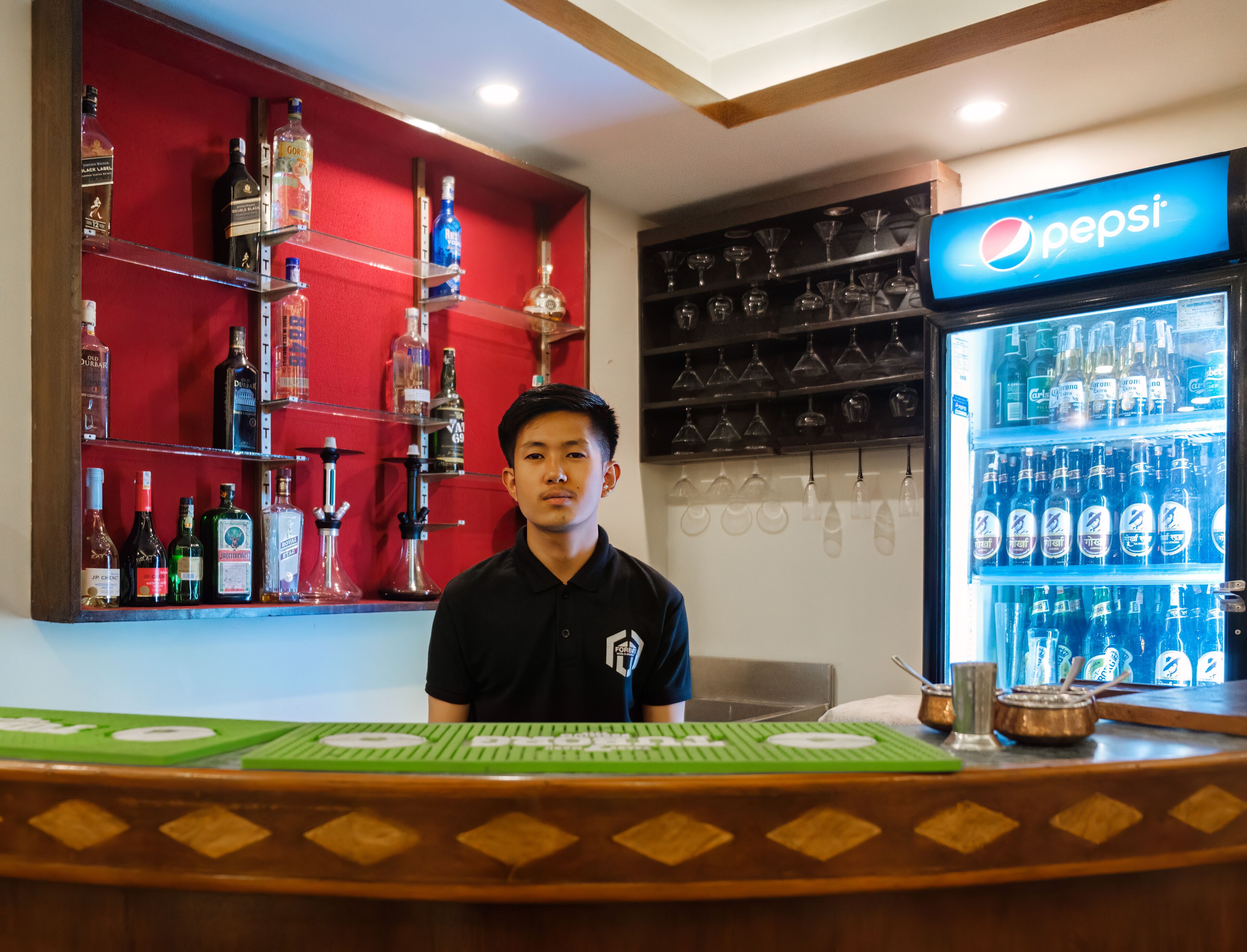 Uma área de bar com prateleiras de garrafas de bebidas e um refrigerador de Pepsi.