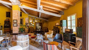 Um interior rústico com vigas de madeira, lareira de tijolos e móveis antigos.