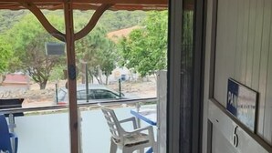 Uma área externa coberta com teto de madeira, chão de ladrilho de pedra e vista para estacionamento com placa indicando "PARKING".