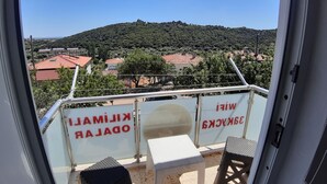 Uma varanda com vista para uma colina, uma cadeira e uma mesa.