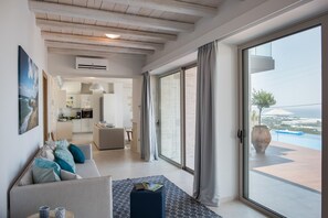 Sala moderna com sofá, mesa de centro e vista para a cozinha e área externa.
