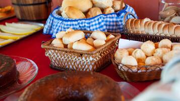 Uma mesa com diversos produtos de panificação, incluindo pães, doces e um bolo.