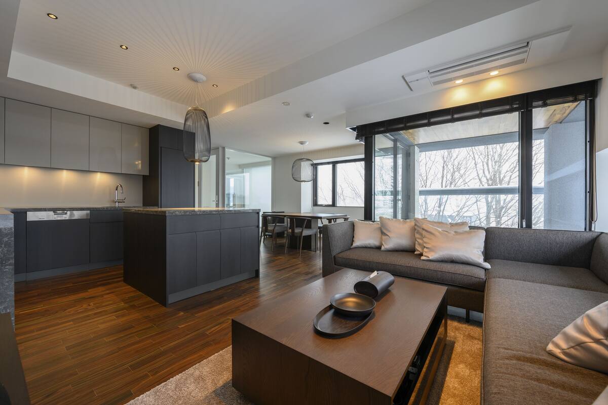 Cozinha moderna com armários escuros, uma ilha central e um espaço de refeições com mesa e cadeiras.