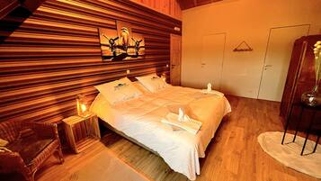 Um quarto aconchegante com uma cama grande, paredes de madeira e uma pequena mesa de cabeceira.