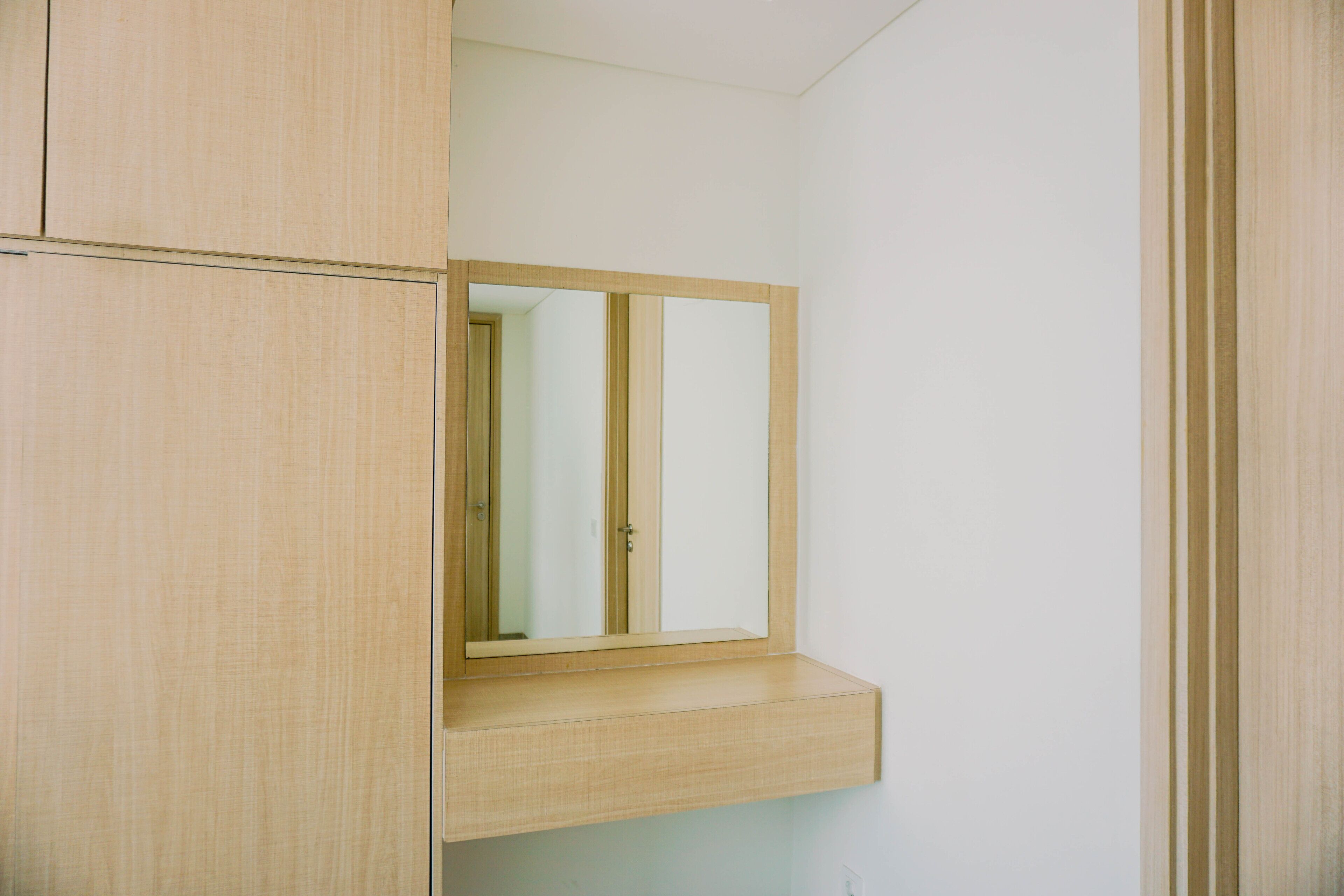 Quarto com guarda-roupa de madeira e espelho sobre uma prateleira.